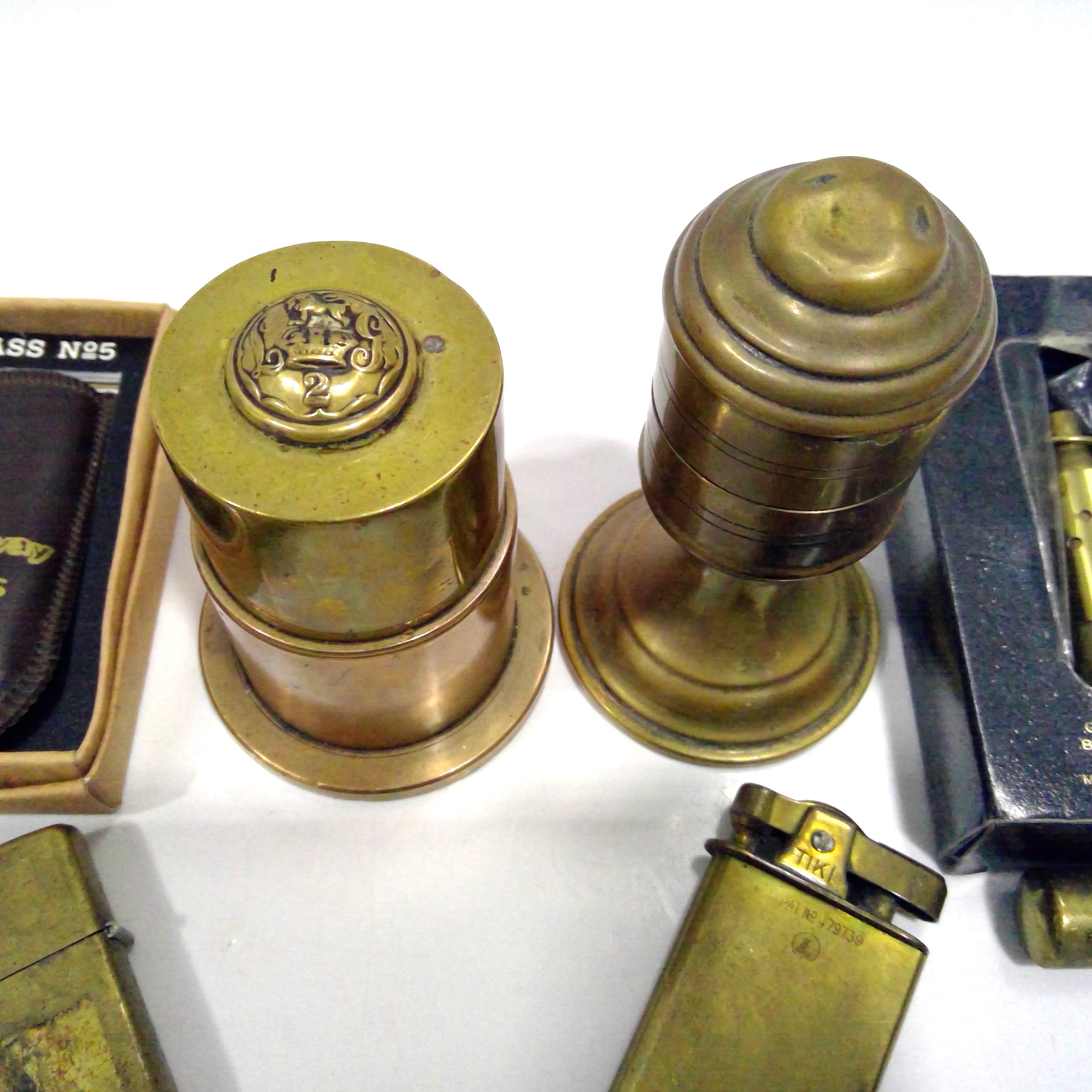 Lot 64 - Two trench art brass table lighters the