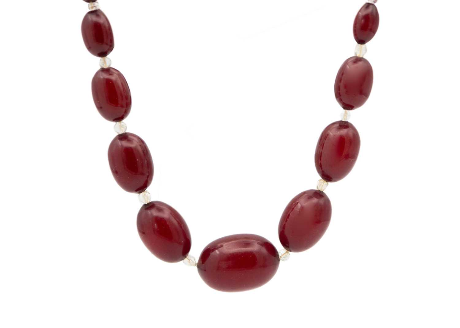 Lot 49 - A cherry amber bakelite and paste bead