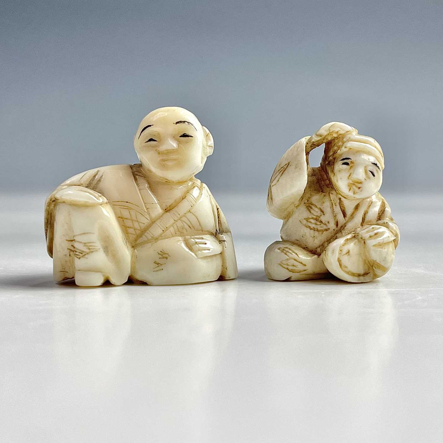 Lot 557 - Two small Japanese ivory netsukes of seated