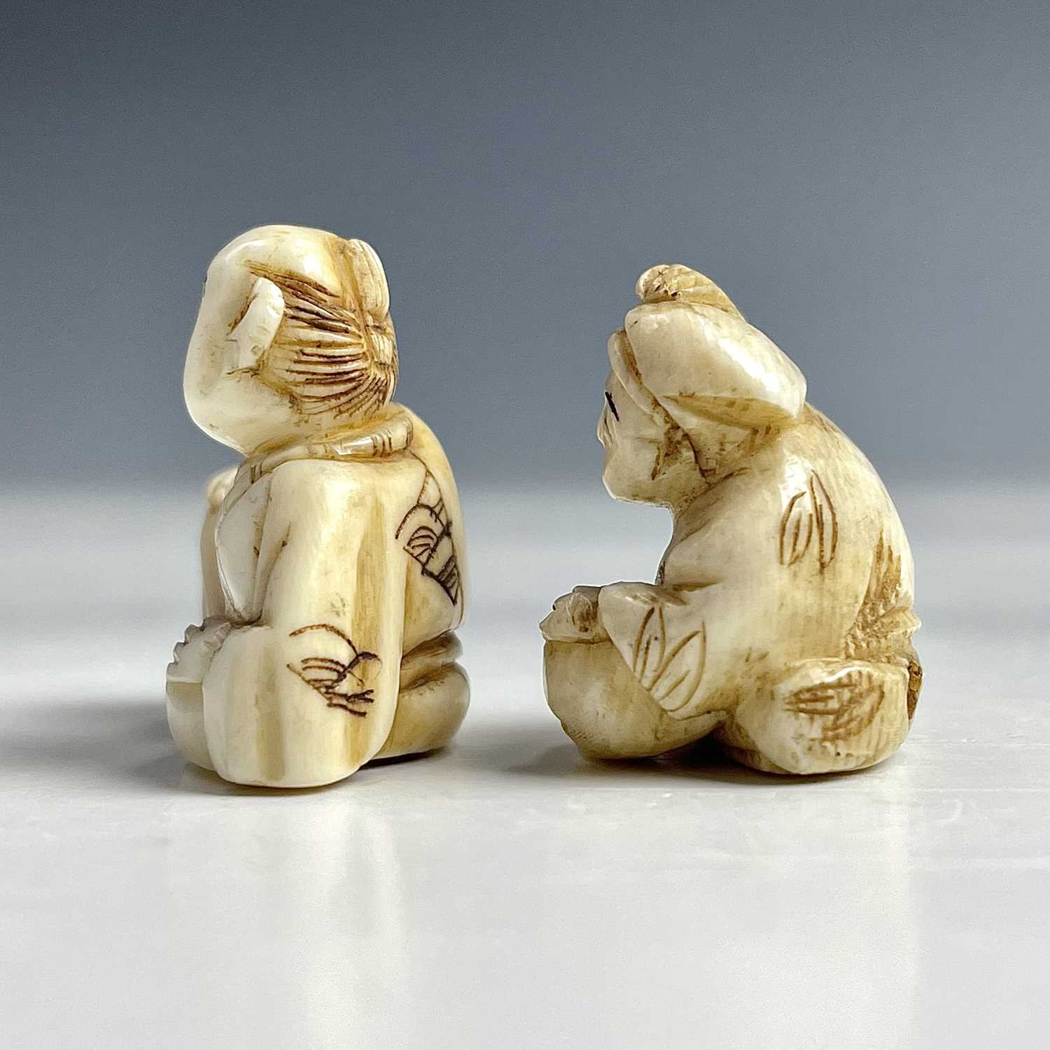 Lot 557 - Two small Japanese ivory netsukes of seated